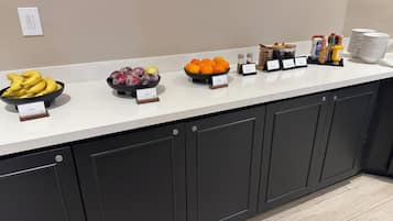 Um balcão de buffet com diversas frutas e acompanhamentos.
