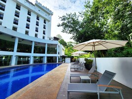 Um hotel moderno com piscina, espreguiçadeiras e guarda-sóis.