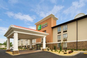 Um hotel Holiday Inn Express com entrada coberta, fachada de pedra e estacionamento.
