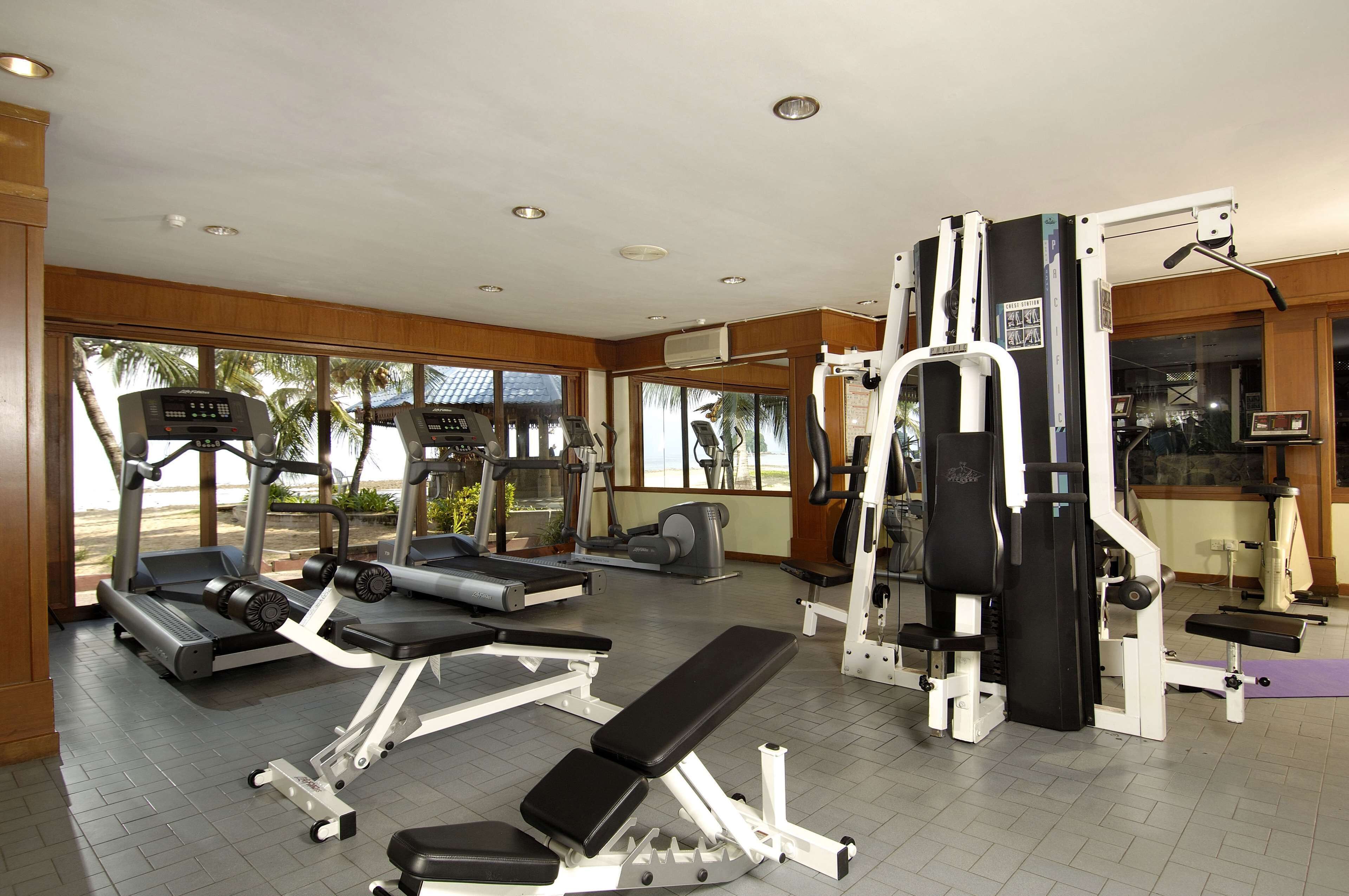 Uma academia com esteiras, aparelhos de musculação e um banco.