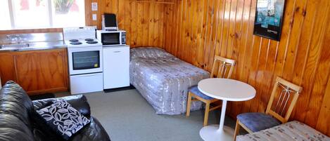 Quarto compacto com cozinha compacta, uma cama, um sofá e uma pequena mesa.