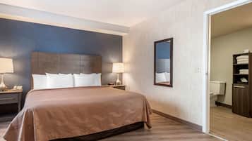 Quarto de hotel com uma cama grande, duas mesas de cabeceira com luminárias, um guarda-roupa e um espelho na parede.