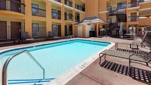 Um hotel com piscina, área de estar ao ar livre e várias varandas.