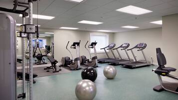 Uma academia com esteiras, elípticos e bolas de exercício.