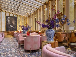 Um hall de hotel luxuoso com pé-direito alto, piso estampado e assentos elegantes.