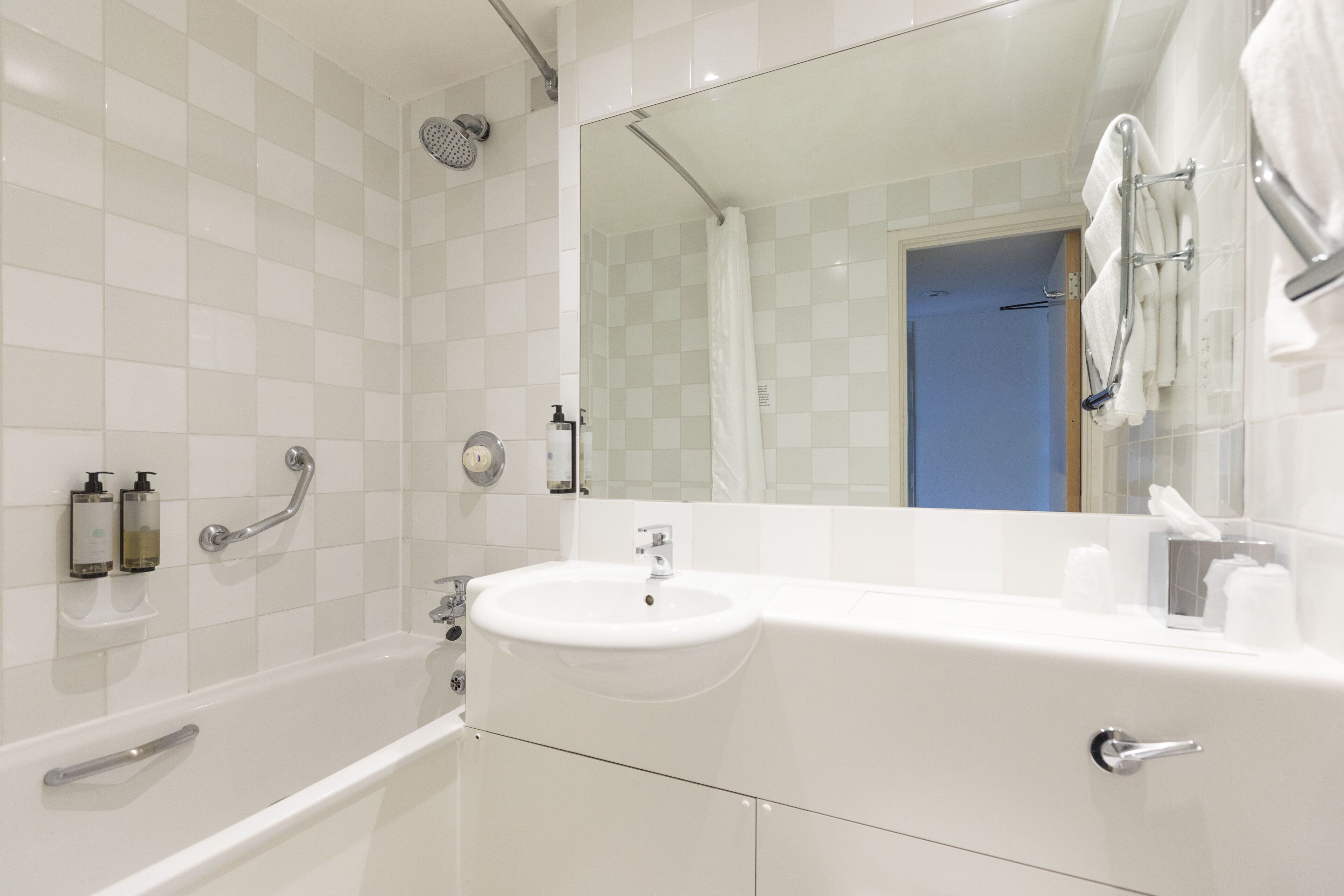 Uma casa de banho moderna com lavatório branco, banheira e chuveiro.