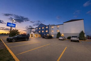 Um hotel com estacionamento, vários edifícios e uma placa indicando ser um AmericInn by Wyndham.