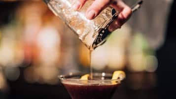 Uma mão servindo uma bebida em uma taça de martini.