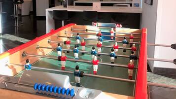 Uma mesa de futebol de mesa em um saguão de hotel, com uma televisão e obras de arte nas paredes.