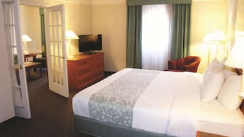 Quarto de hotel com uma cama, televisão, escrivaninha com cadeira e janela com cortinas.