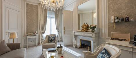 Um quarto luxuoso com lustre, lareira, sofá, mesa de centro e estante de livros.