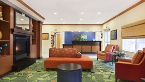 Um hall de hotel com lareira, área de estar e balcão de recepção.