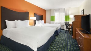 Quarto de hotel com duas camas, uma escrivaninha, uma televisão e uma cadeira.