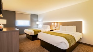 Quarto de hotel com duas camas, uma escrivaninha e uma janela.