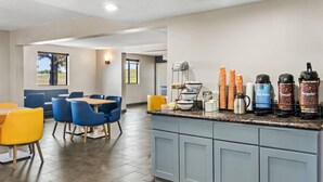 Um saguão de hotel moderno com área de estar, um espaço para café e vista para o exterior.