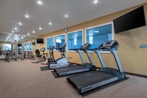 Uma academia com esteiras, bicicletas ergométricas e aparelhos de musculação.