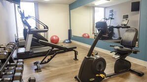 Uma academia com equipamentos de cardio, halteres e bolas de exercício.