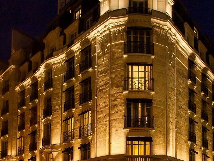 Um hotel de vários andares com design arquitetônico clássico, com janelas em arco e uma entrada imponente.