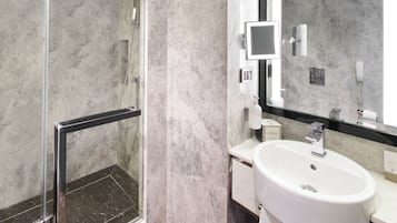 Casa de banho moderna com cabine de duche em vidro, lavatório branco e espelho grande.