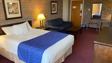 Quarto de hotel com uma cama grande, um sofá, uma escrivaninha e um espelho.