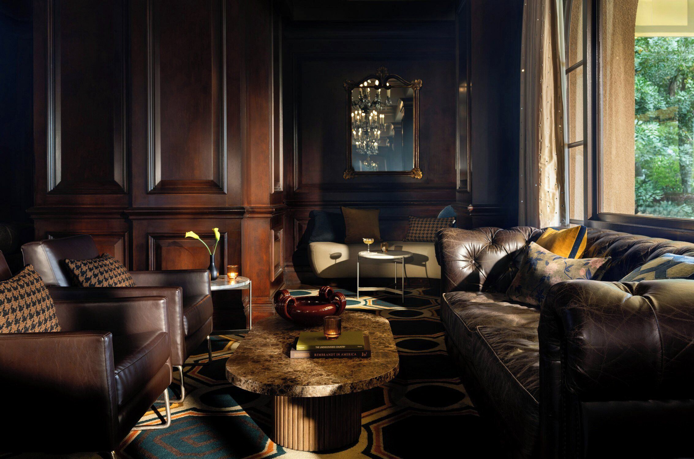 Uma sala de estar luxuosa com sofás de couro, uma mesa de centro e um candelabro.