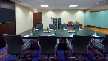 Uma sala de conferências com uma mesa comprida, seis cadeiras e uma tela de projeção.