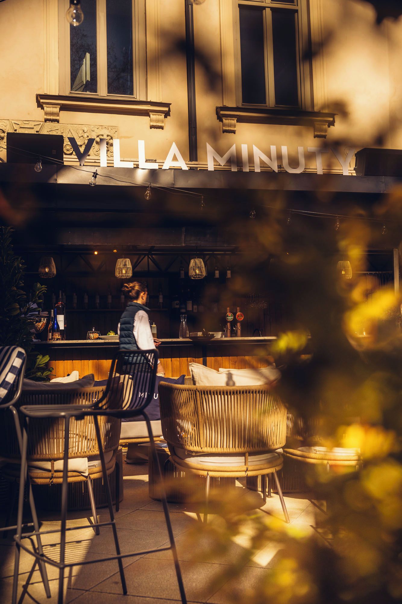 Espaço de estar ao ar livre com cadeiras de vime e um balcão de bar na Villa Minuty.