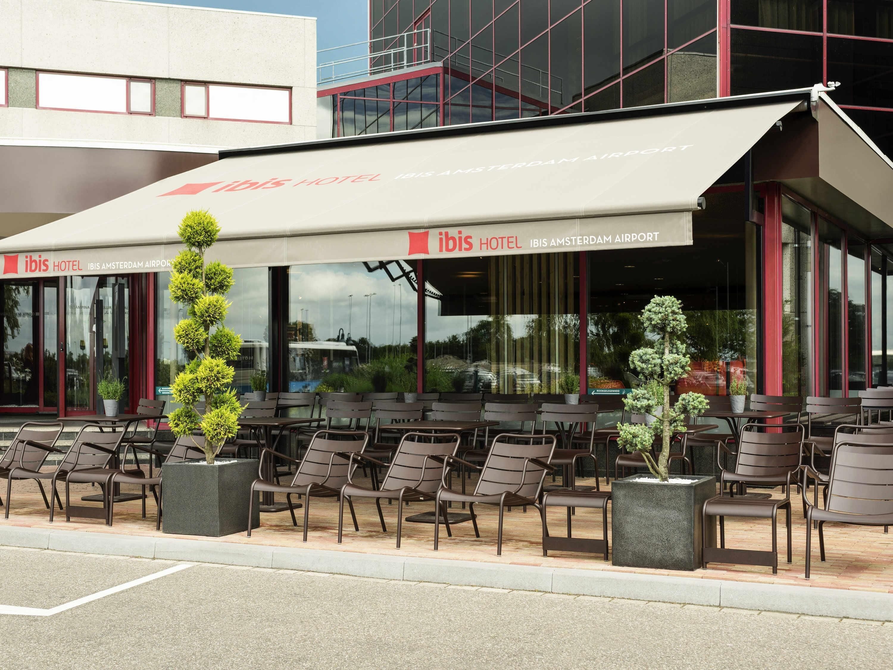 Uma área externa com mesas e cadeiras e plantas em vasos no hotel ibis.