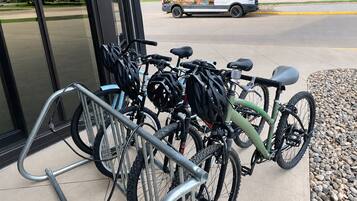 Bicicletas estacionadas em frente a um prédio com entrada de vidro.