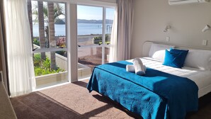Quarto de hotel com uma cama, vista para o mar e porta de vidro deslizante.