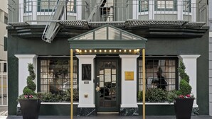 Um edifício com fachada escura, uma entrada destacada com porta e duas janelas grandes de cada lado.