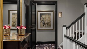 Um corredor com um quadro, uma escada e um número indicando o andar.