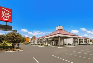 Um Red Roof Inn com telhado vermelho, paredes brancas e estacionamento.