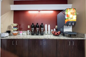 Cozinha com estação de café, tigela de frutas e dispensador de suco.
