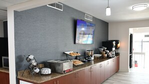 Uma cozinha moderna com bancada de granito, eletrodomésticos de aço inoxidável e televisão de tela plana na parede.