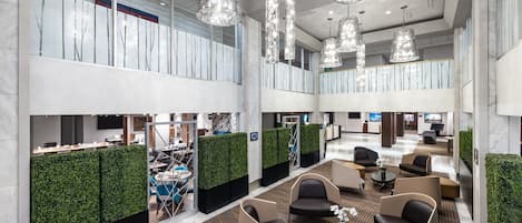 Um hall amplo com móveis modernos, painéis de parede verdes e luminárias pendentes.