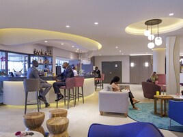 Um espaço lounge moderno com bar, assentos e balcão de recepção.