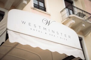 Placa de hotel com o nome 'WESTMINSTER HOTEL & SPA' e um elemento decorativo.