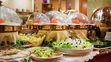 Buffet com diversos pratos cobertos por tampas de vidro em formato de cúpula.