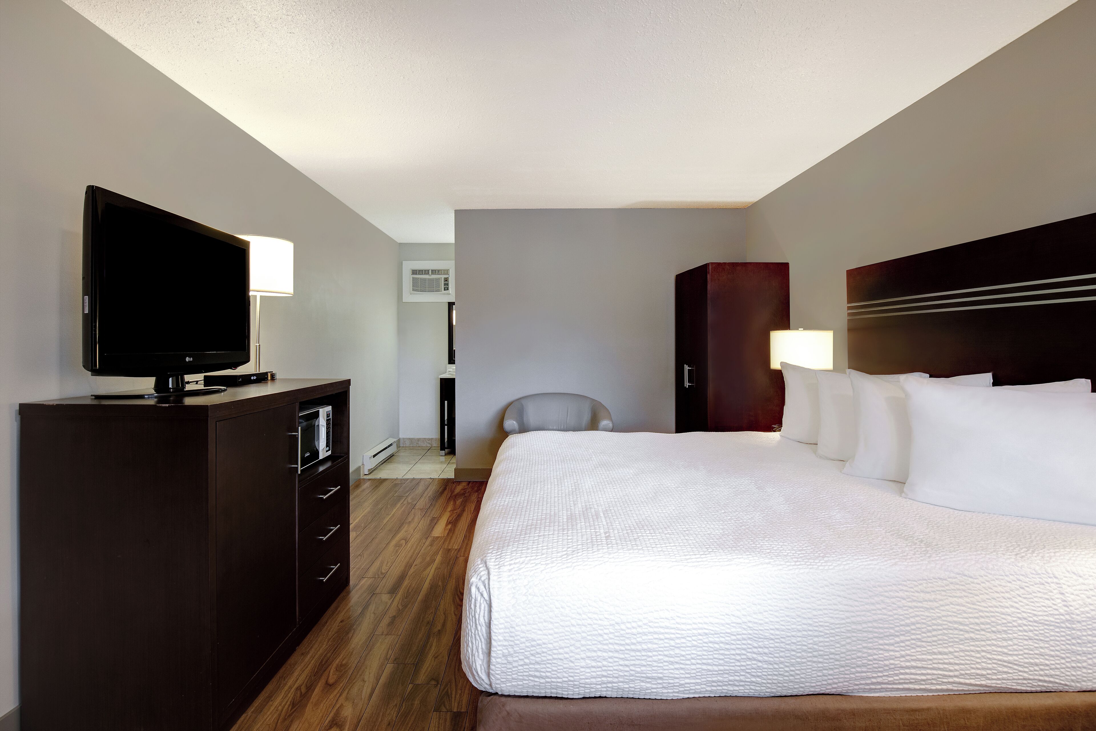 Quarto de hotel com cama grande, televisão em móvel, escrivaninha e uma cadeira.