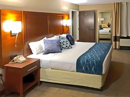 Quarto de hotel com uma cama grande, telefone de mesa e criado-mudo.