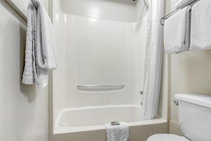 Um banheiro com banheira, vaso sanitário e porta-toalhas.