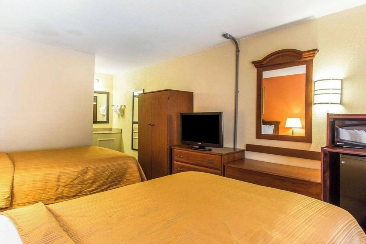 Quarto de hotel com duas camas, televisão, penteadeira e espelho.