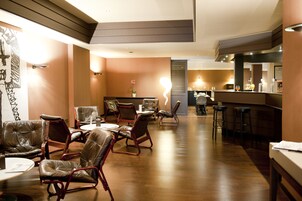 Um saguão de hotel com poltronas de couro, área de bar e balcão de recepção.