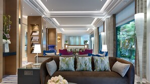 Um hall moderno com um sofá marrom, uma mesa de centro de vidro e um arranjo de flores.