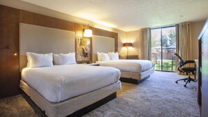 Quarto de hotel com duas camas, uma janela grande e vista para o exterior.