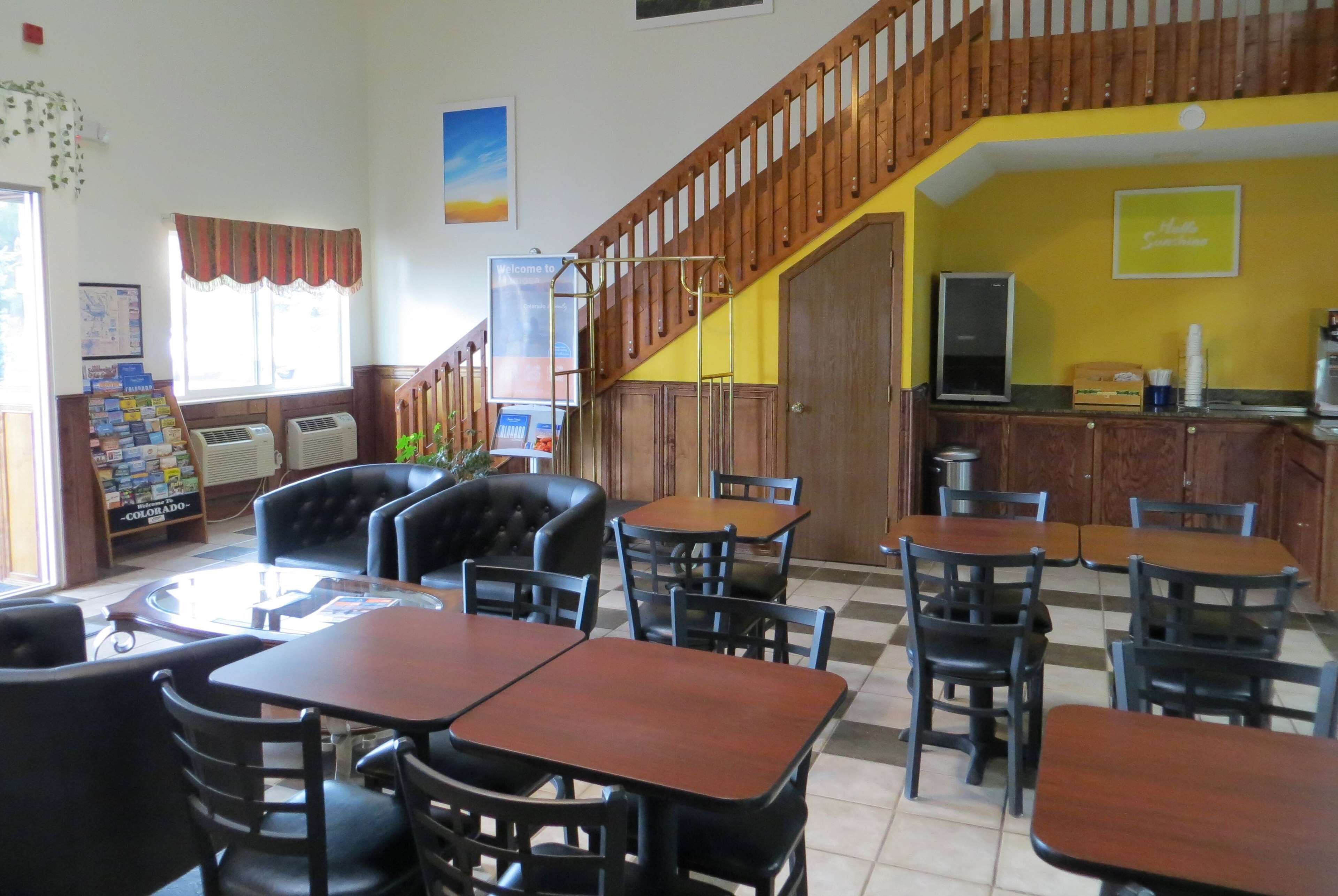 Um restaurante com várias mesas, cadeiras, uma escada e um balcão.