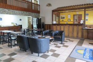 Um saguão de hotel com balcão de recepção, área de estar com mesas e cadeiras, e um vendendor automático.
