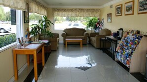 Um hall de hotel com sofá, poltronas, mesa de centro, balcão de recepção e uma seleção de revistas.