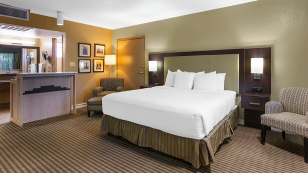 Quarto de hotel com uma cama grande, uma escrivaninha, uma cadeira e uma mesa de cabeceira.